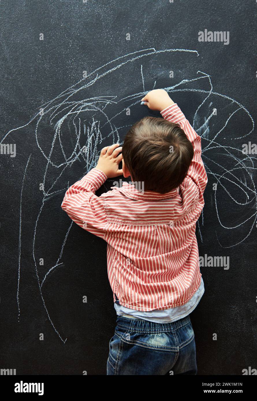 Young child, scribble and art on chalkboard in classroom of preschool ...