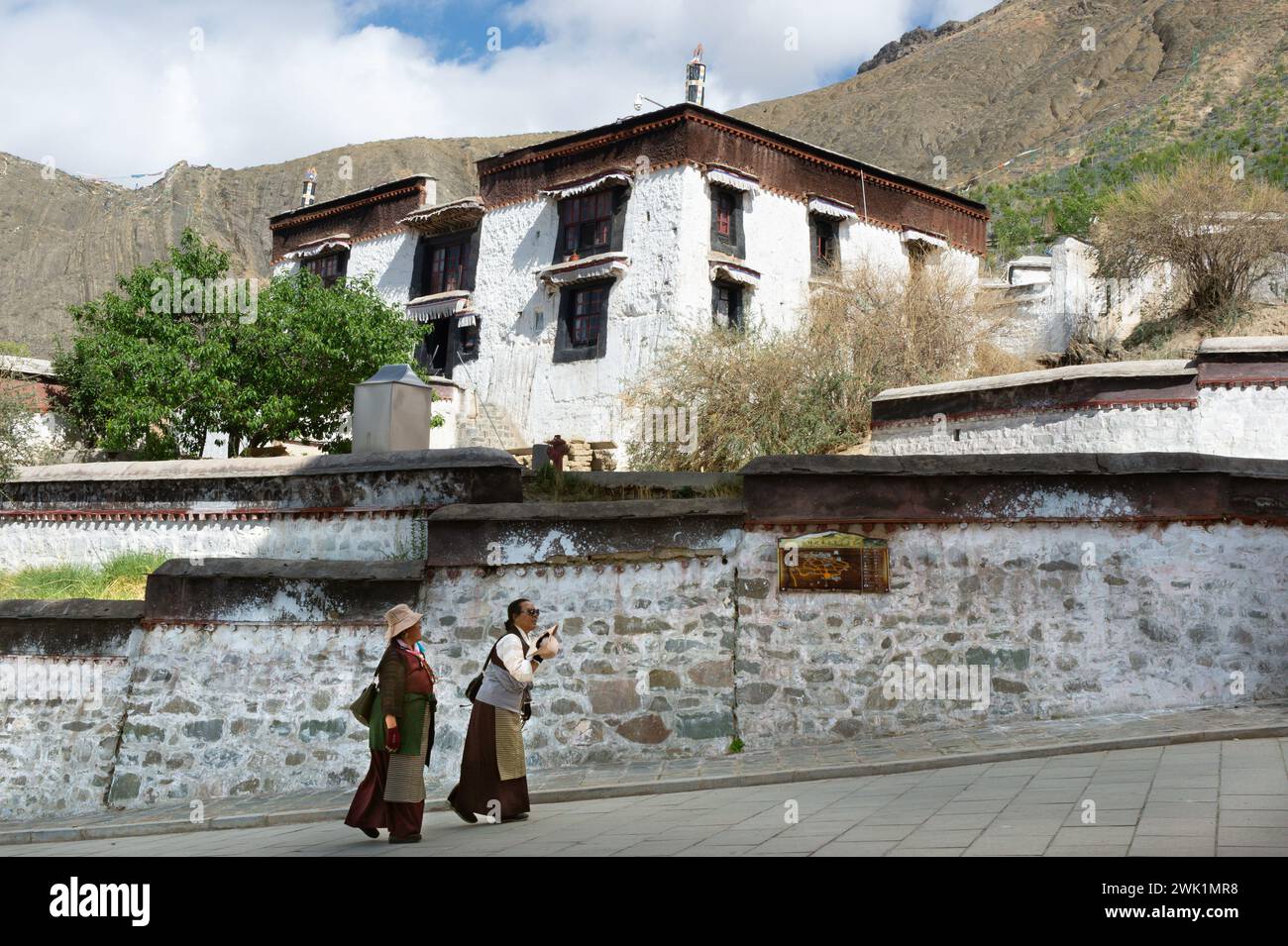 Two women walk along the outside wall of Tashi Lhunpo Monastery in Shigatse, Tibet Autonomous ...