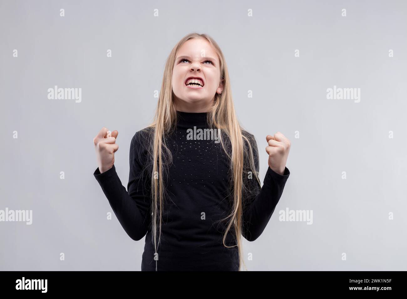 Young girl's intense expression and raised fists express a powerful ...