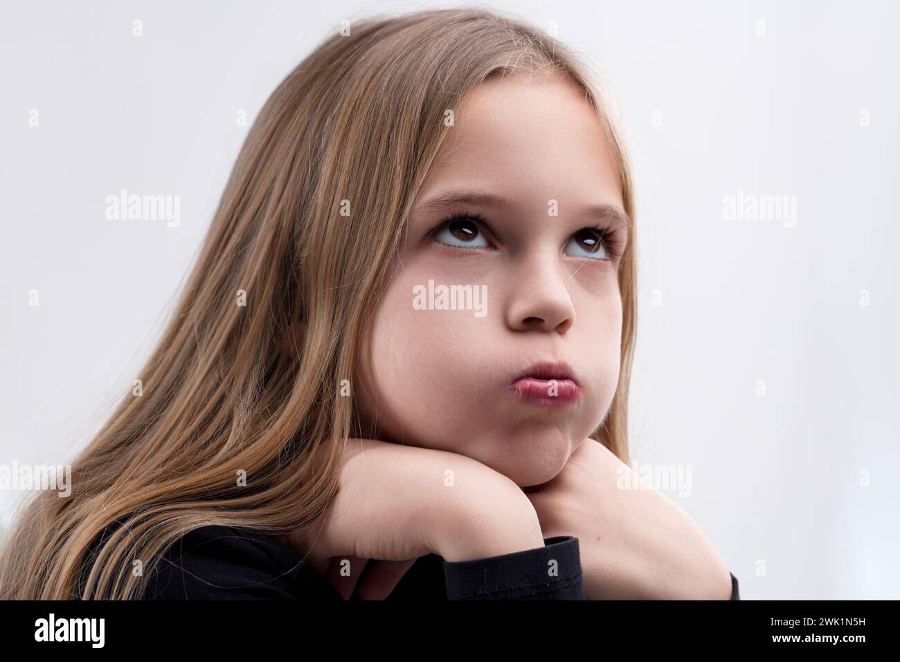 Thoughtful young girl with a pout, contemplating deeply with a ...