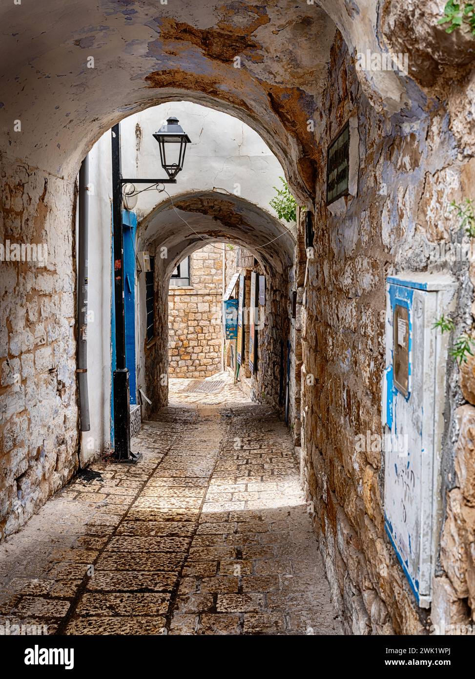 A narrow street with arched passaageways between buildings is located ...