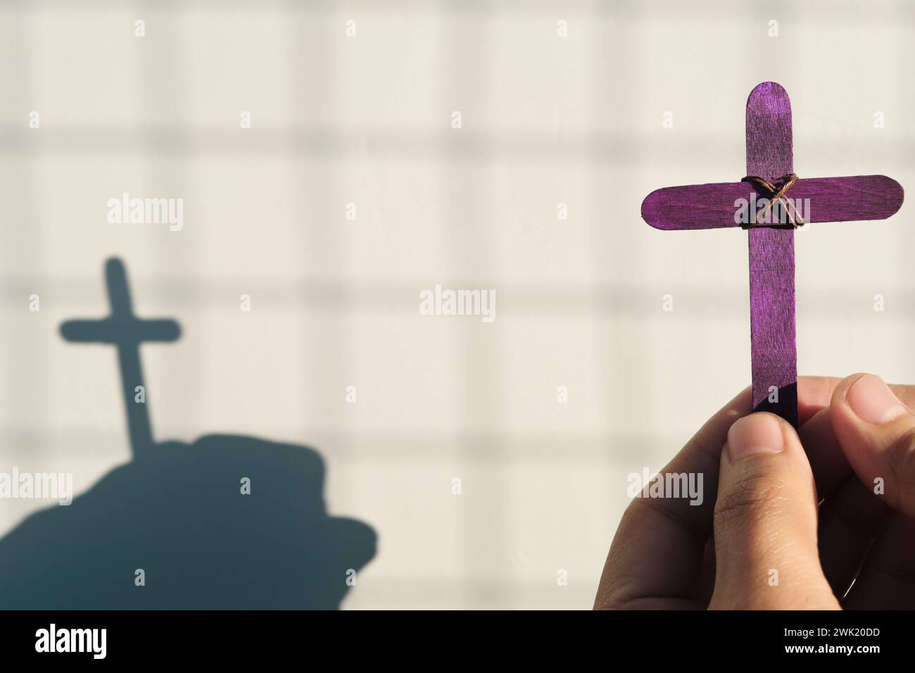 Male hand holding purple wooden cross with shadow. Christianity, faith ...