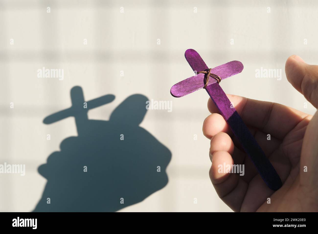 Male hand holding purple wooden cross with shadow. Christianity, faith ...