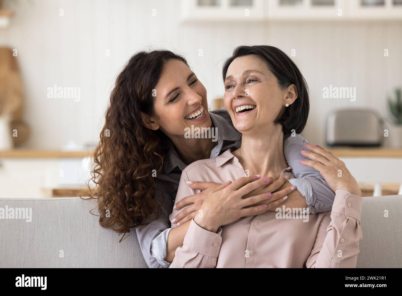 Cheerful grownup daughter cuddling from behind her lovely mature mother Stock Photo - Alamy