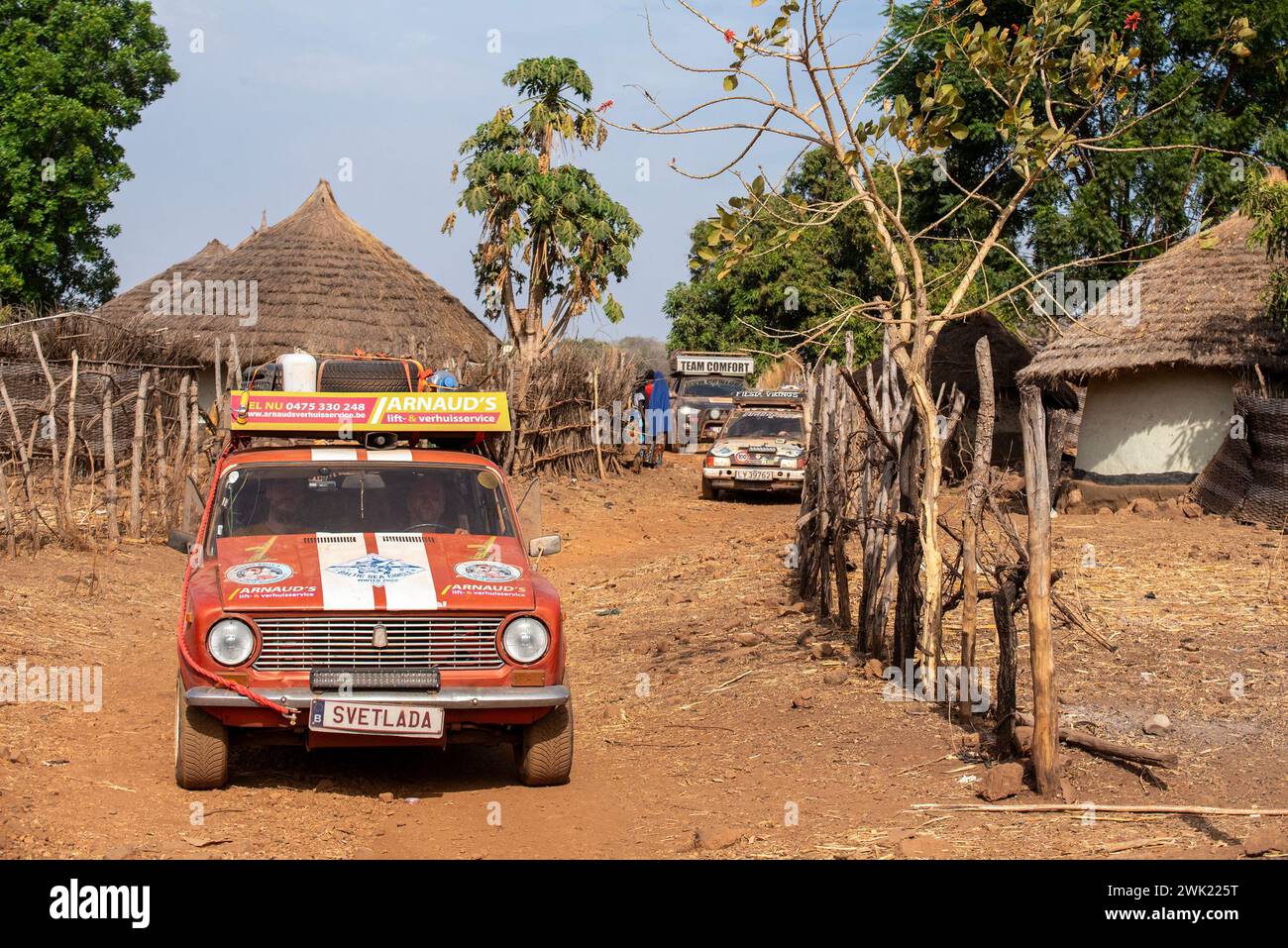Racers drives through a narrow road in Guinea Conakry while locals ...