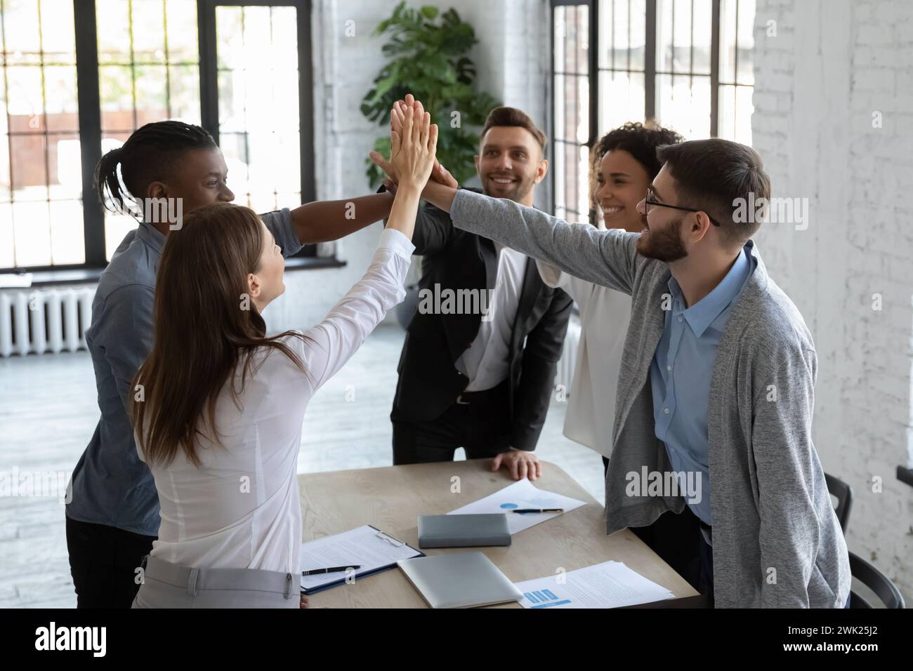 Happy coworkers high-fiving each other to celebrate work success Stock ...