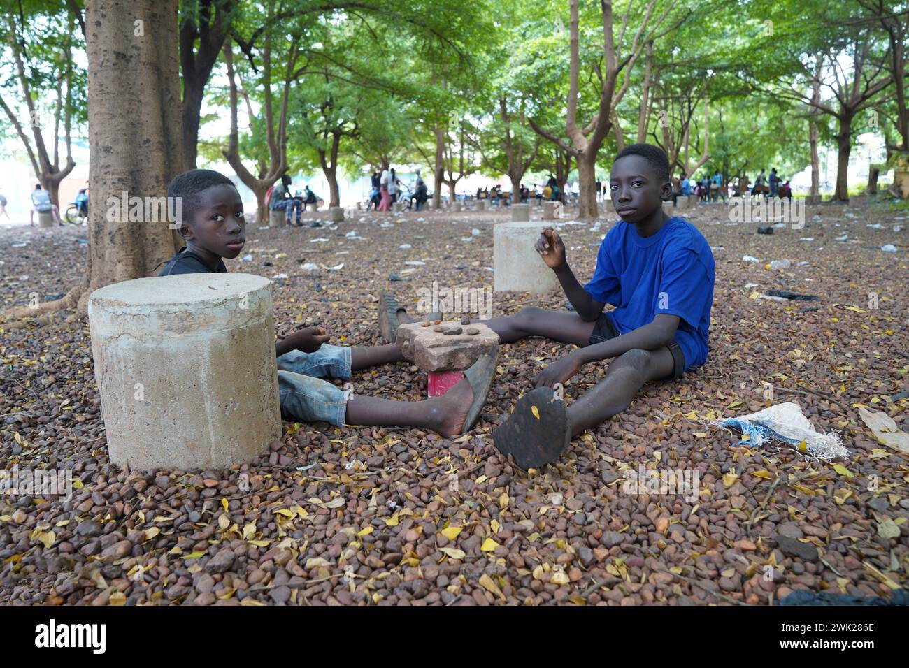 Two small black West African boys sitting in a public park busy playing ...