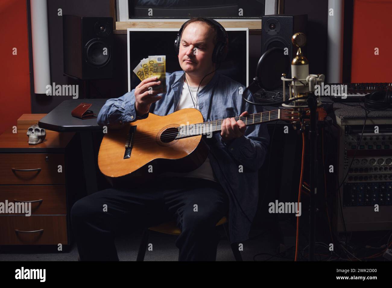 A musician in a recording studio holds euro money in his hands. The ...