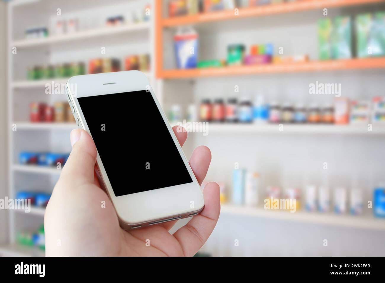 pharmacist hand holding smart phone with blur some shelves of drug in ...