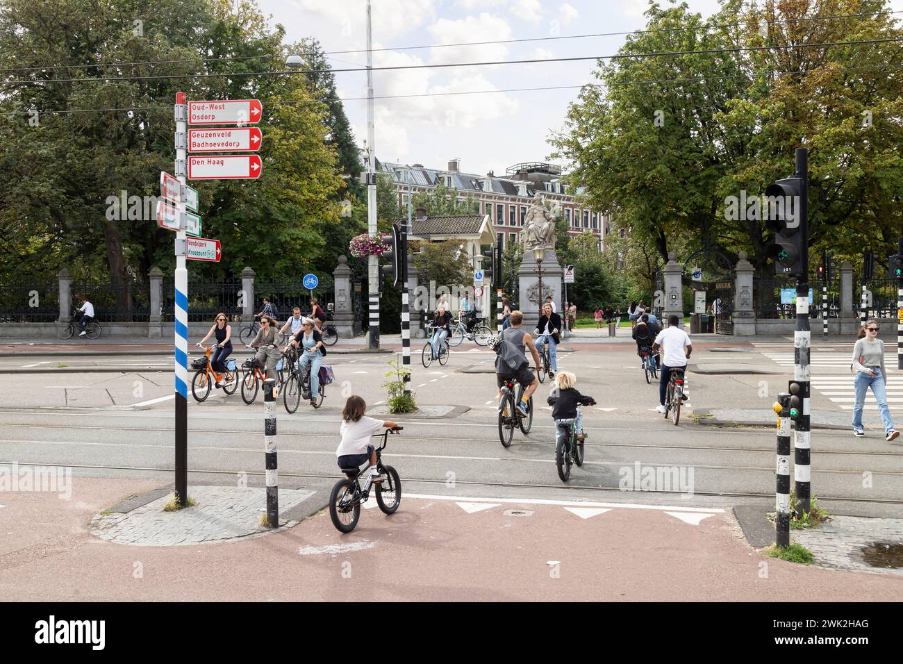 Cyclists cross a busy street to and from the Vondelpark in Amsterdam ...