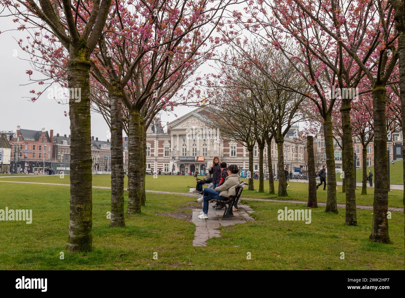 People sit on a bench on the museum square opposite the concert hall in ...
