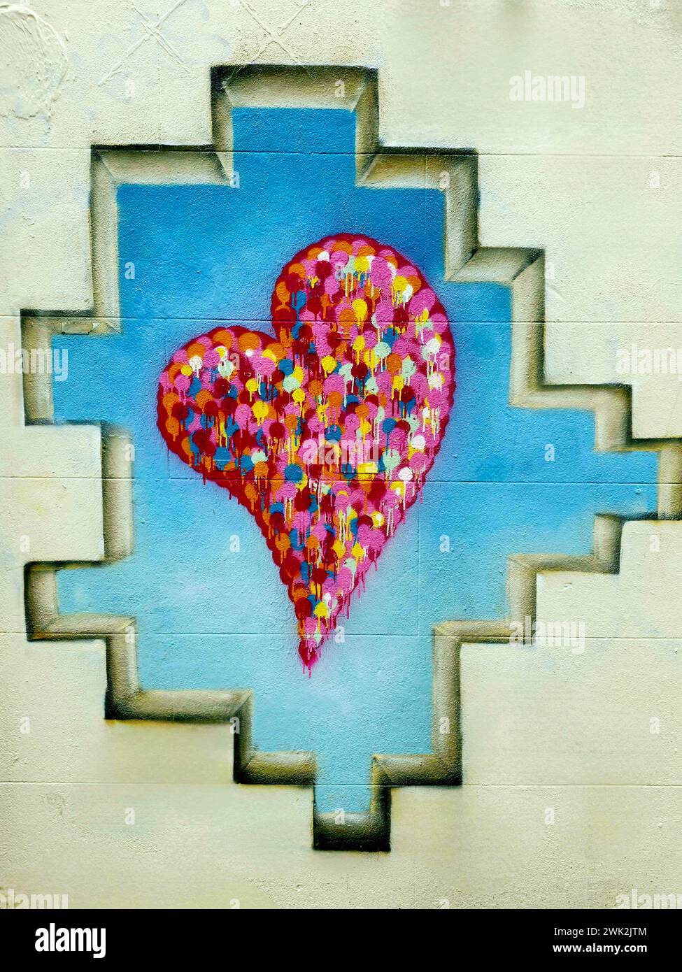 Graffiti mural of a heart inside a painted frame in a brick wall, in ...