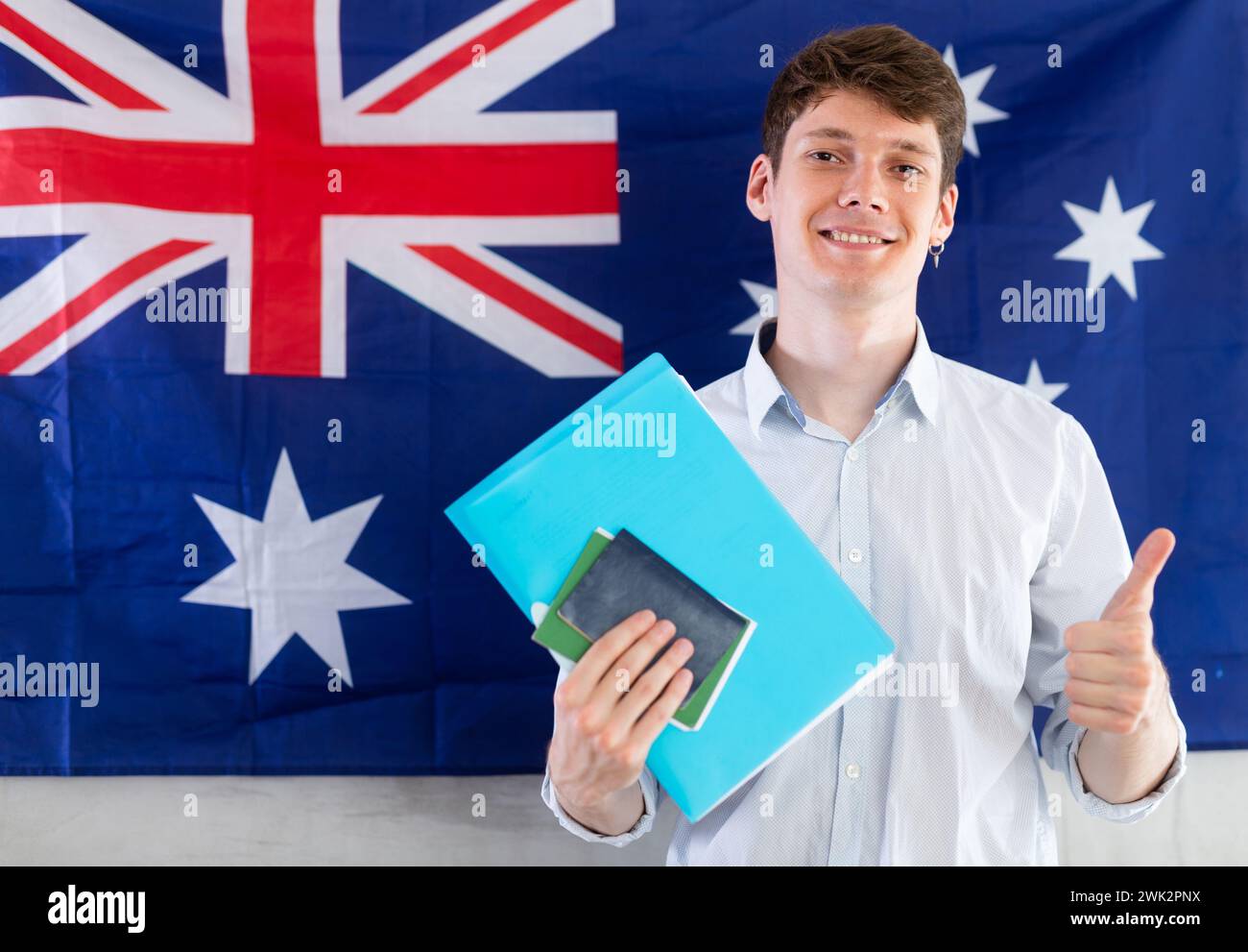 Young guy posing with documents against background of Australian flag ...