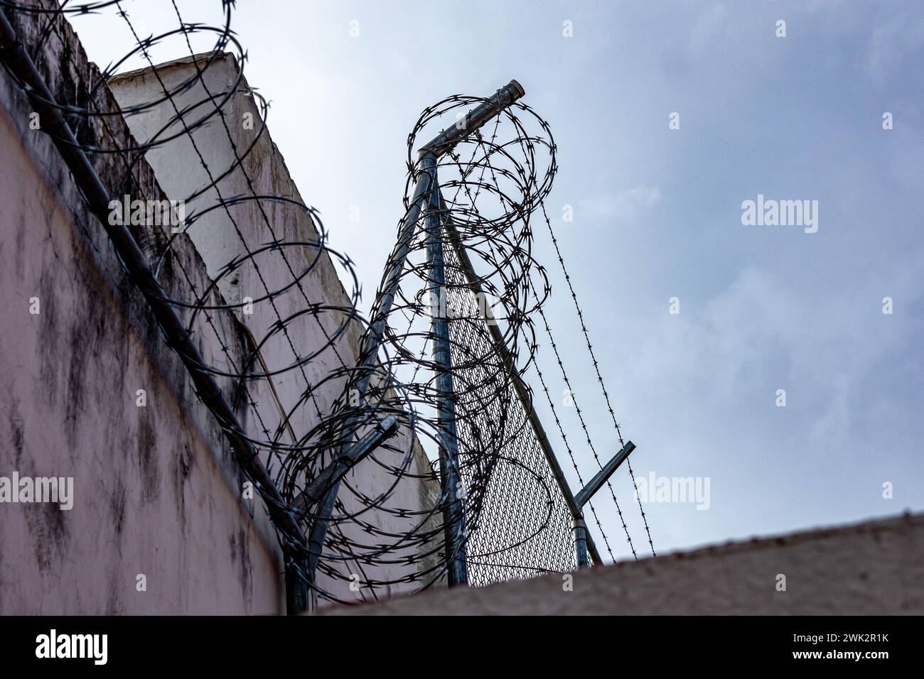 Barbed wire and metal fence on old white walls with black spots of a ...