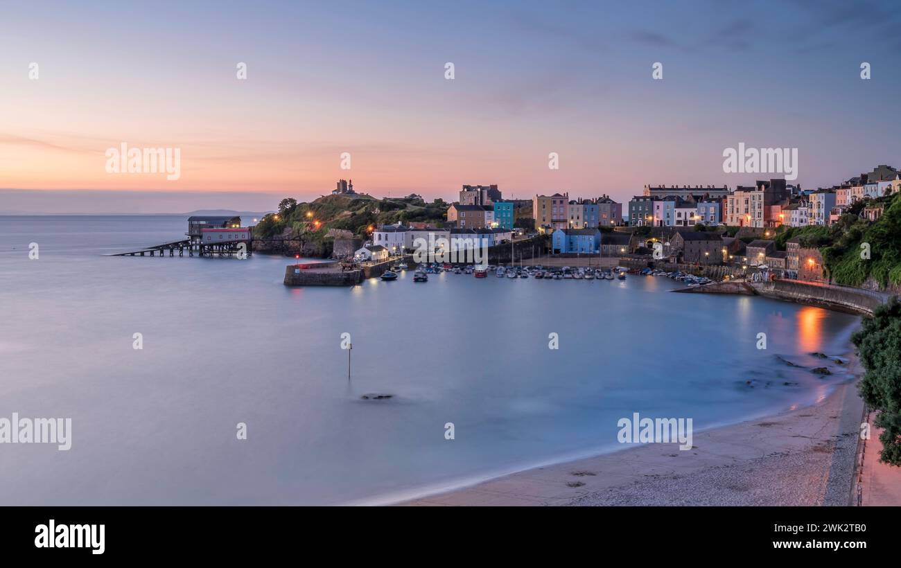Sunrise over Tenby's harbour on a calm summer's morning. Tenby is a ...
