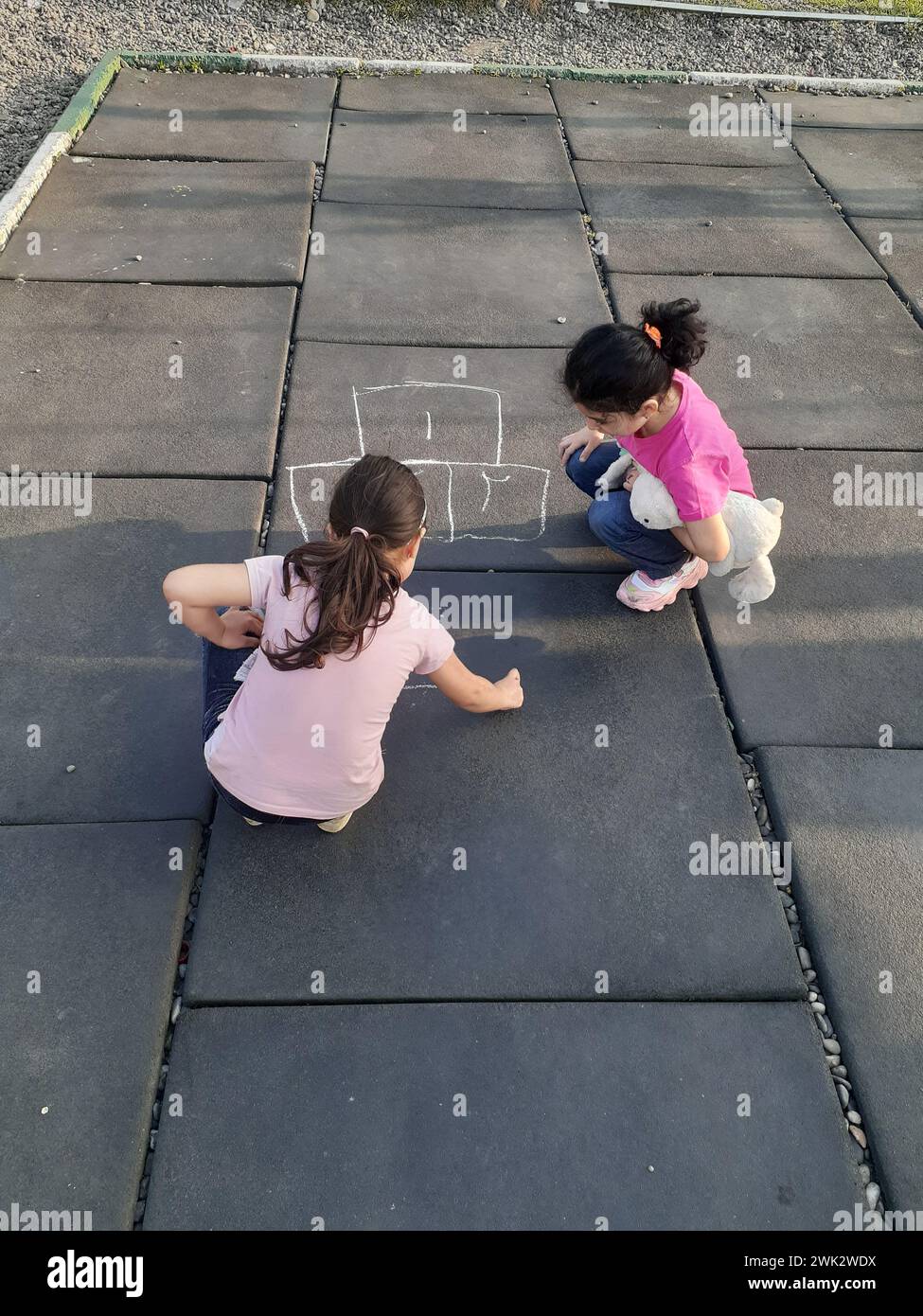 Little girl drawing table by charcoal on square sheets in park ground ...