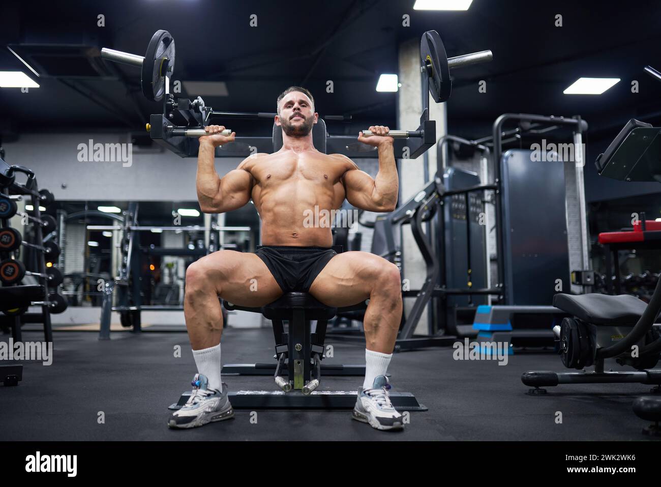 Muscular man with dark hair doing exercise with training apparatus in ...