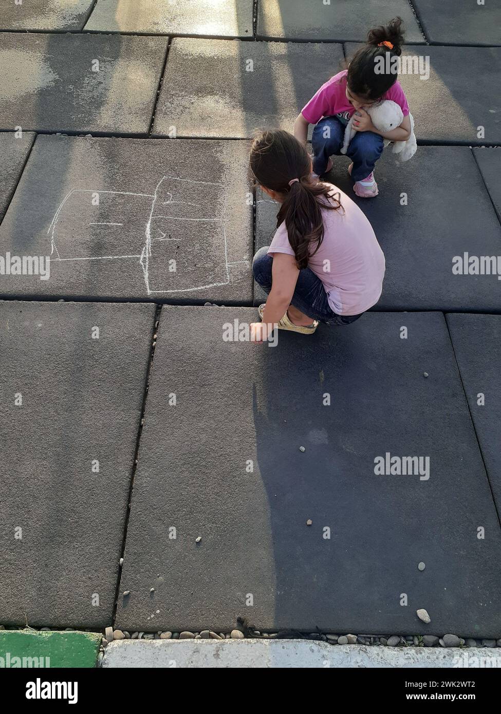 Little girl drawing table by charcoal on square sheets in park ground ...