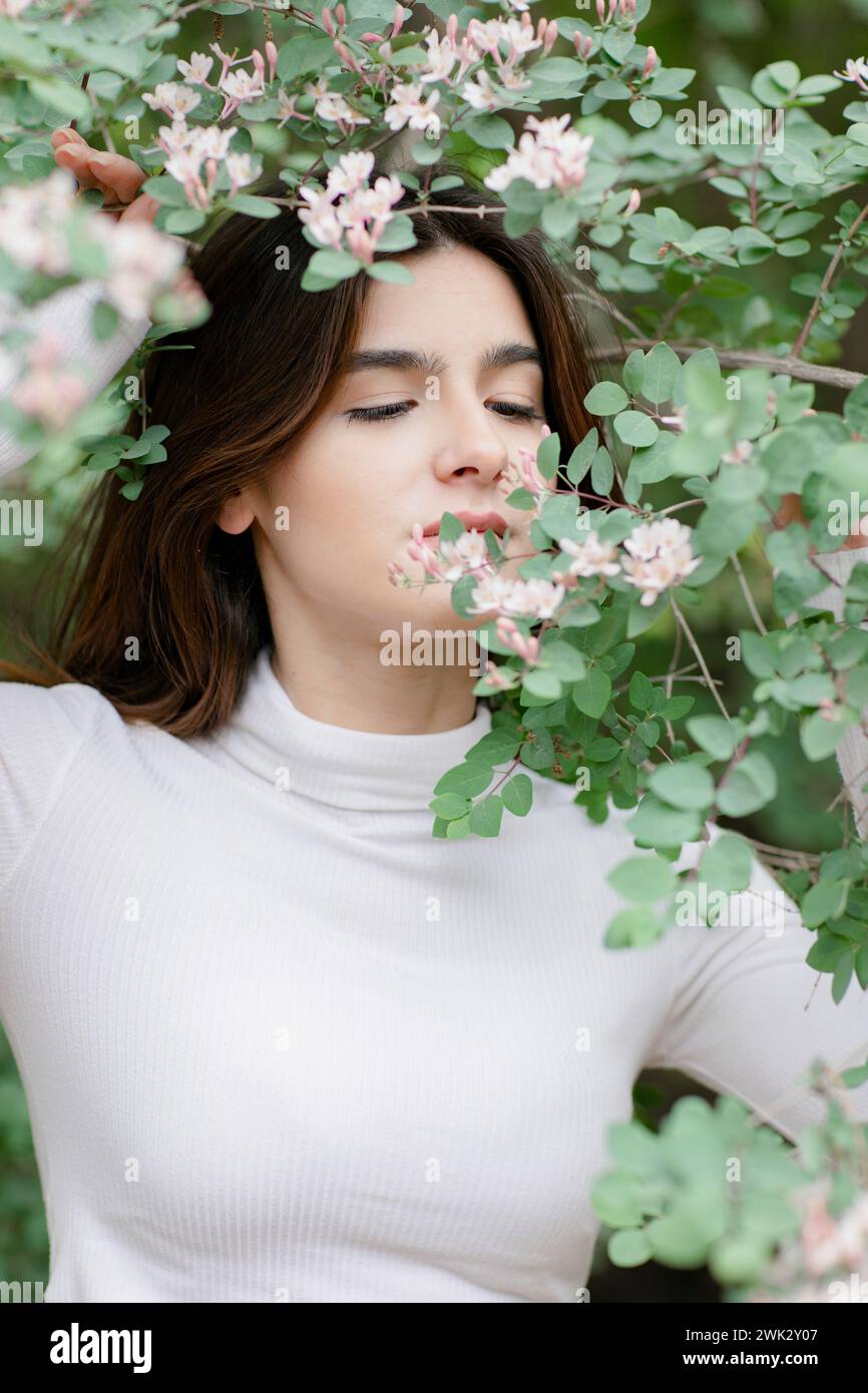 Pretty, brunette girl having photoshoot in park, smelling tree branch ...
