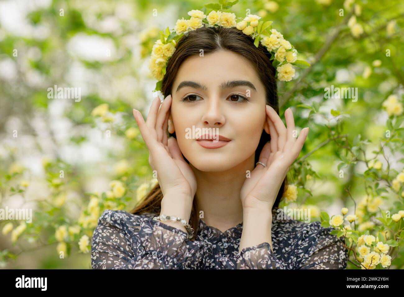 Beautiful girl with flower wreath standing, touching head, looking ...