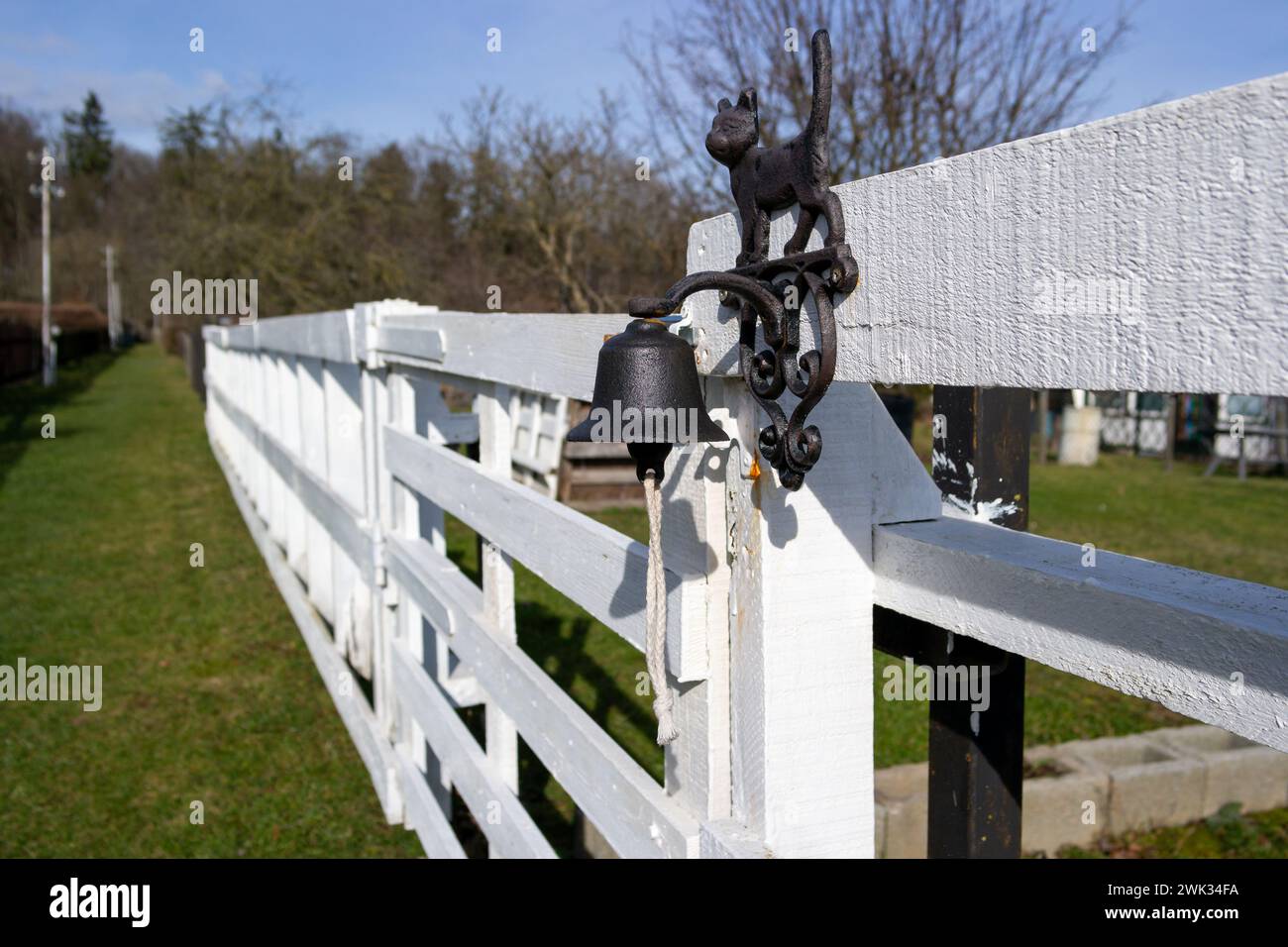 white fence with a metal bell on the garden gate Stock Photo - Alamy