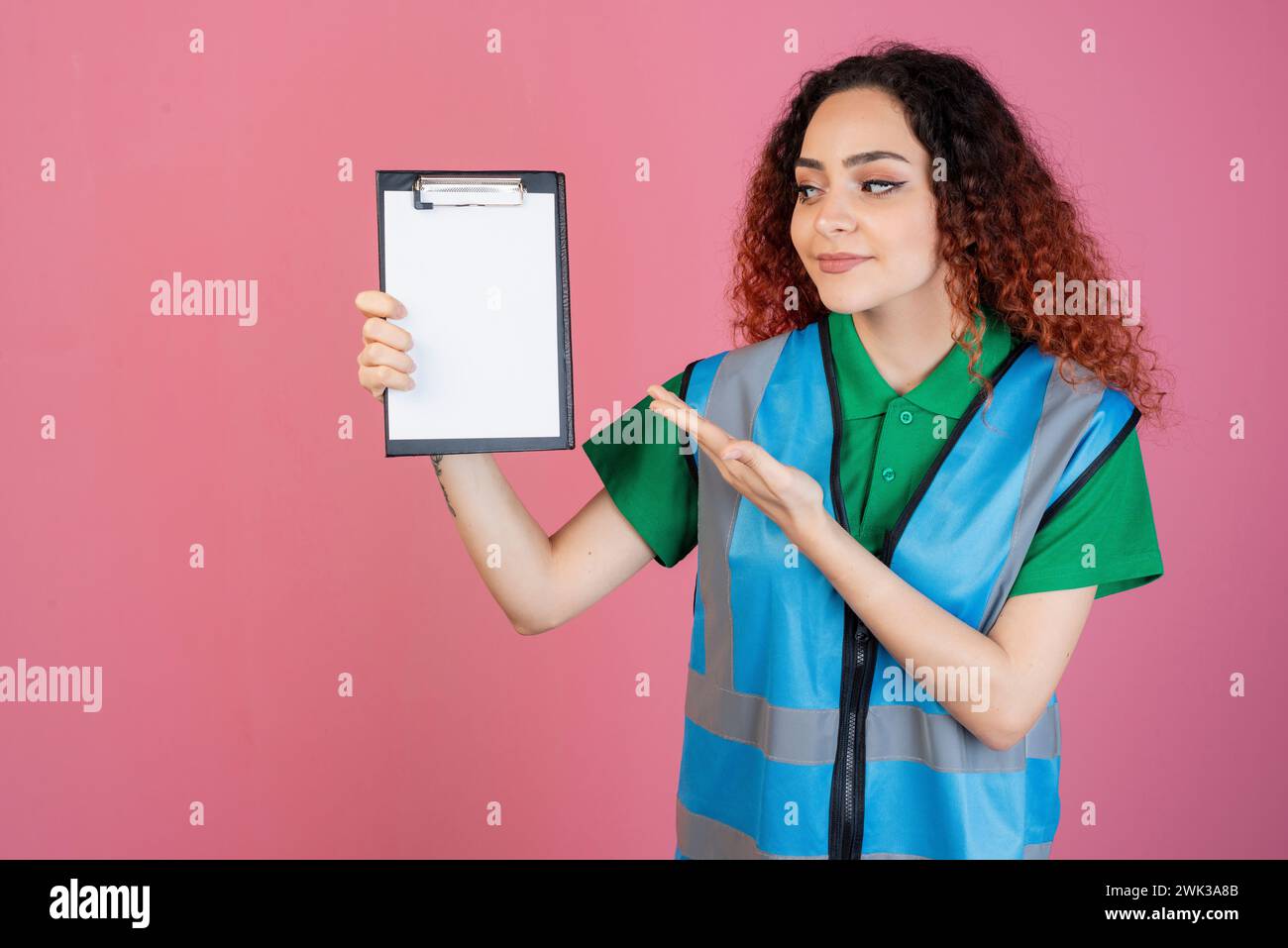Pretty, female paramedic wearing vest, posing indoors, holding folder ...