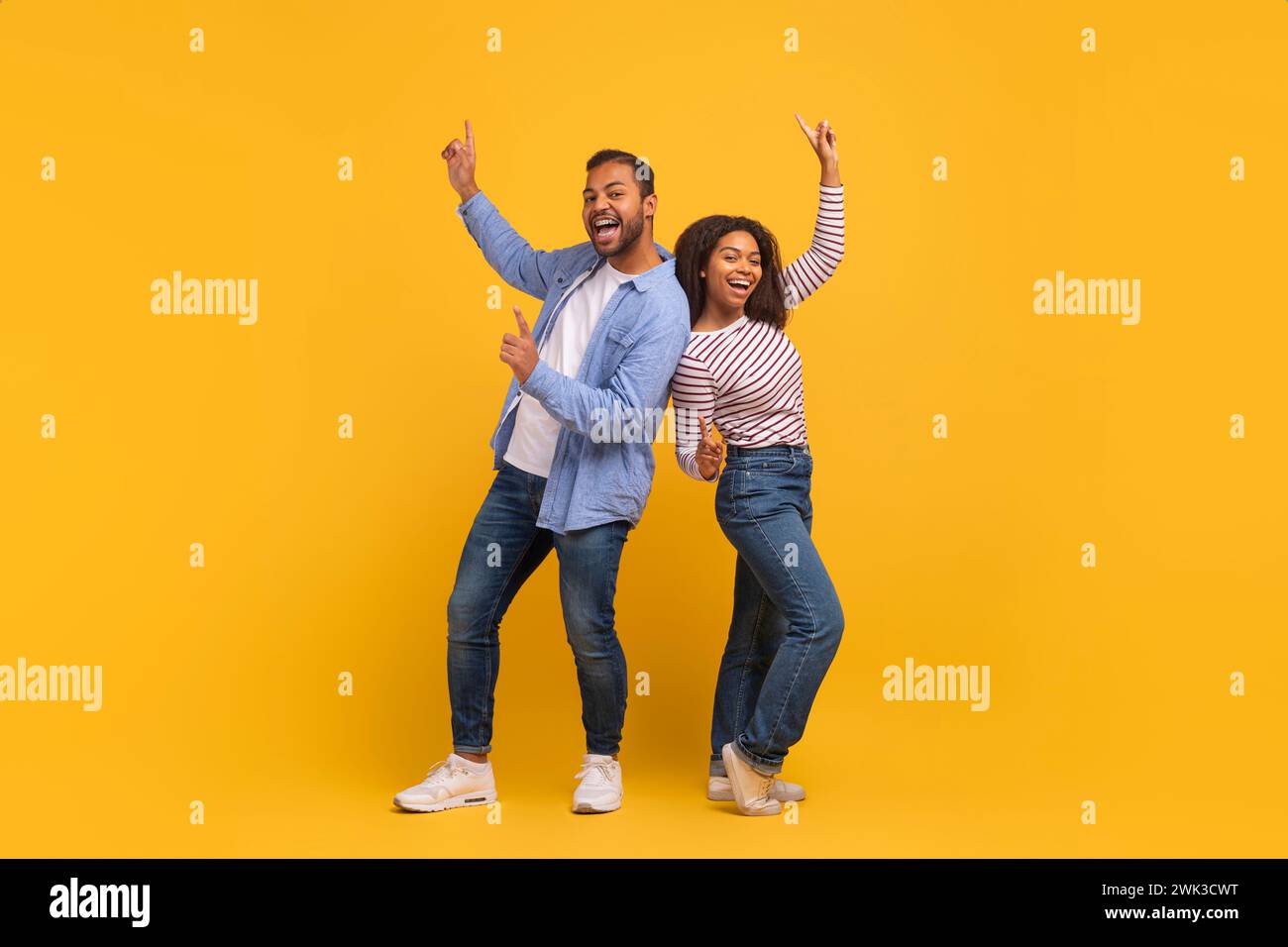 Energetic young black couple dancing with joy, pointing fingers up ...