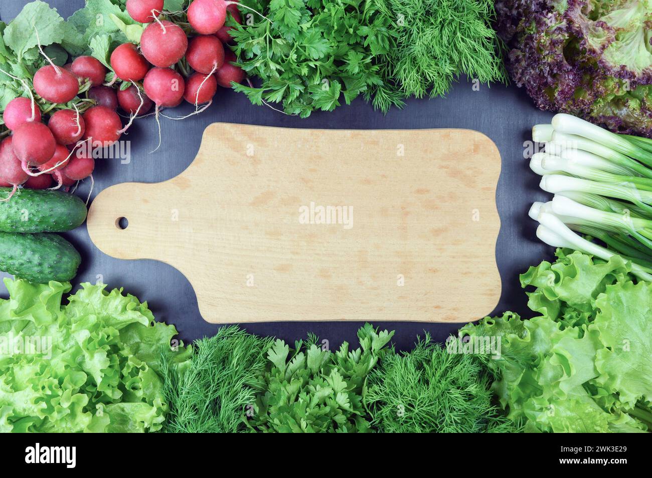 Various vegetables , fresh greens and spices and empty cutting board ...