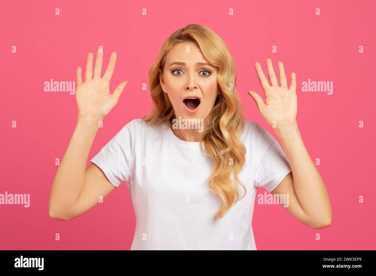 Shocked emotional blonde woman got caught with raised arms, studio ...