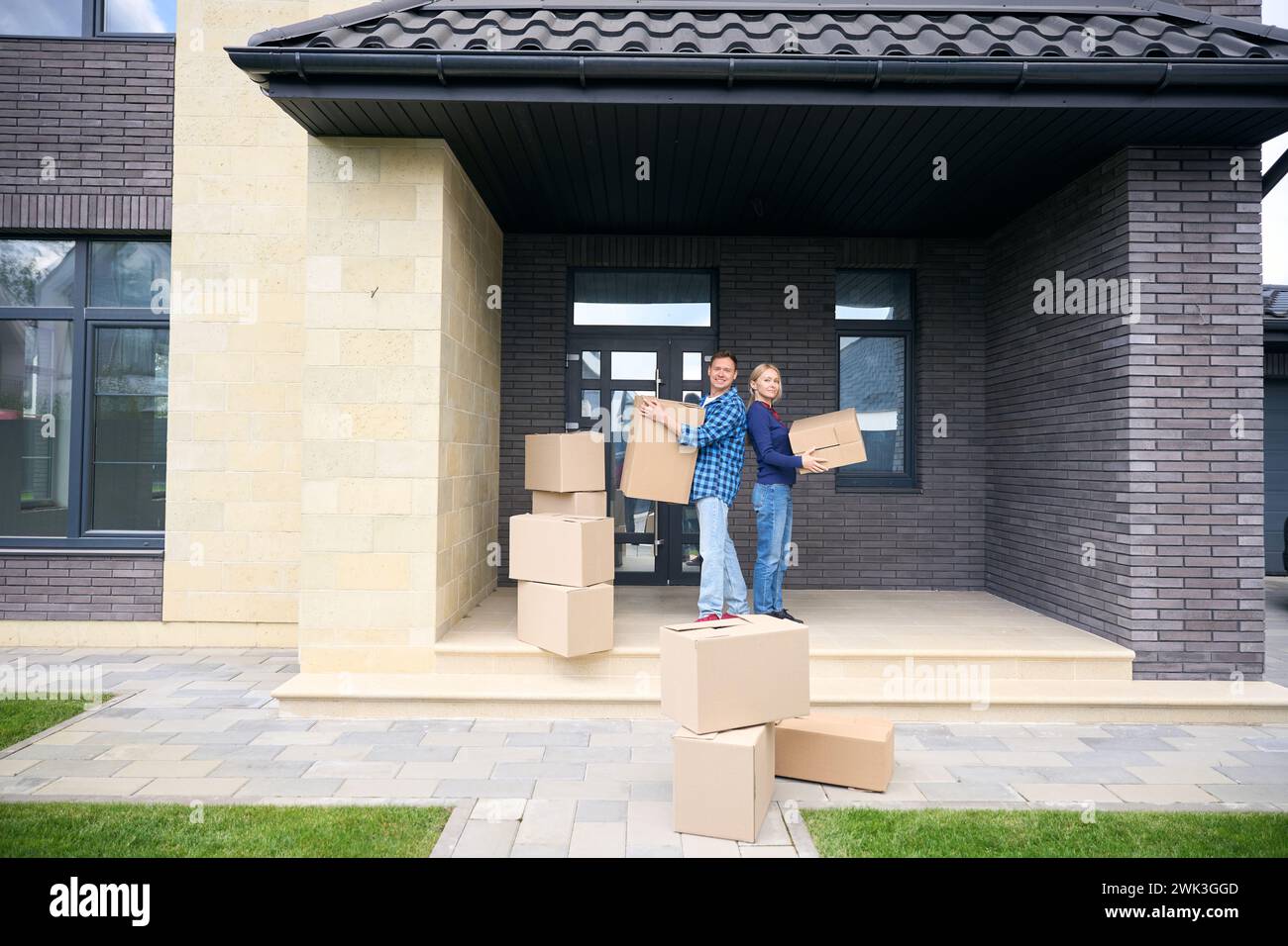 Lady and man holding boxes and standing on porch Stock Photo - Alamy