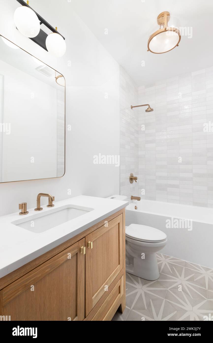 A bathroom with an oak cabinet, white marble countertop, pattern tile ...