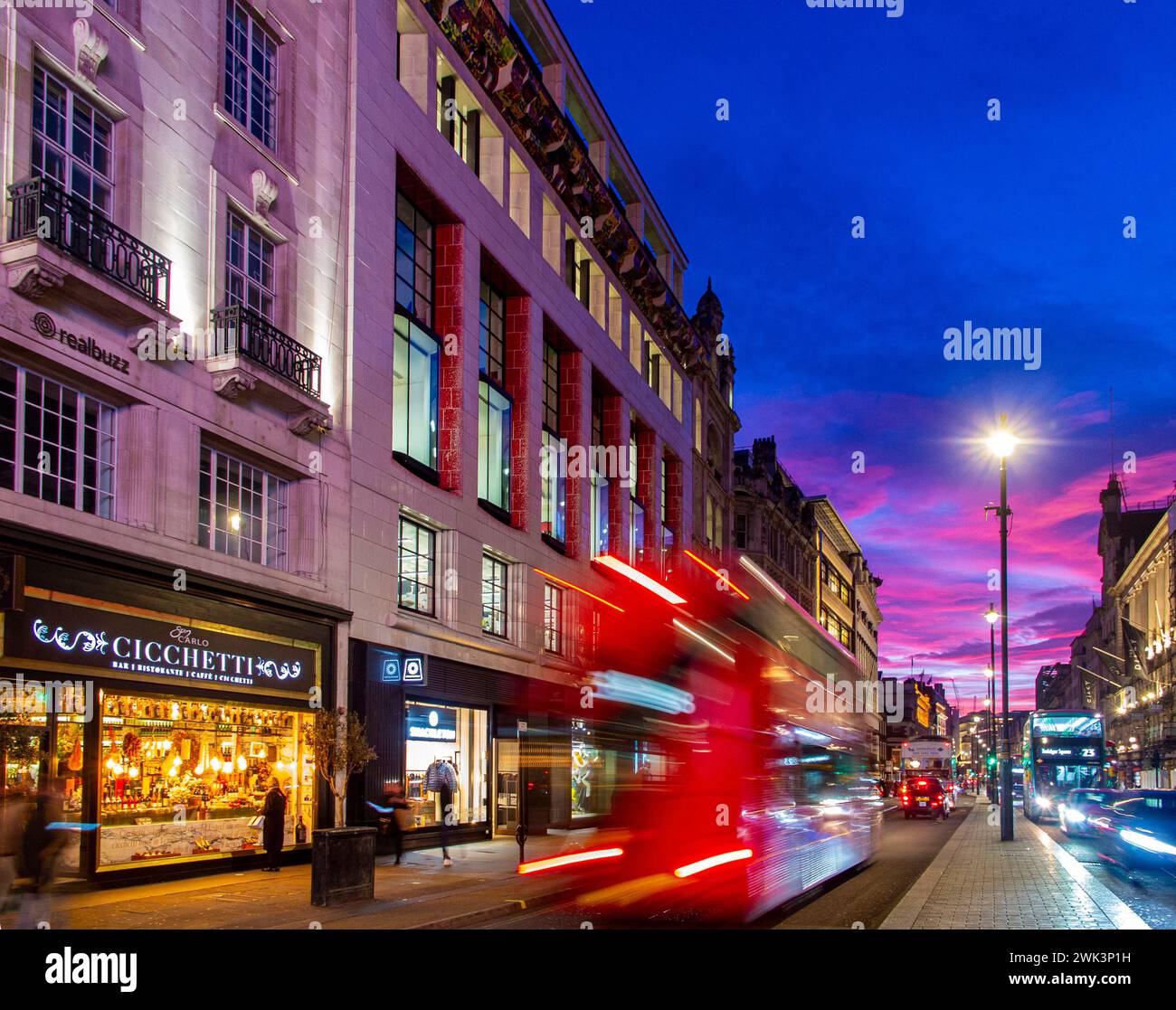 A blurred bus in traffic on Picadilly in London with a dramatic sunset ...