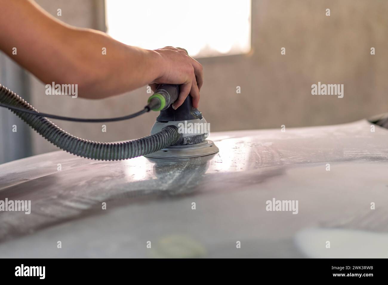 Grinder in the hands of a man who sharpen a car varnish in the car shop ...