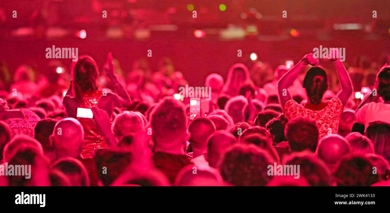 people at the live music concert with red lights and many with cell ...
