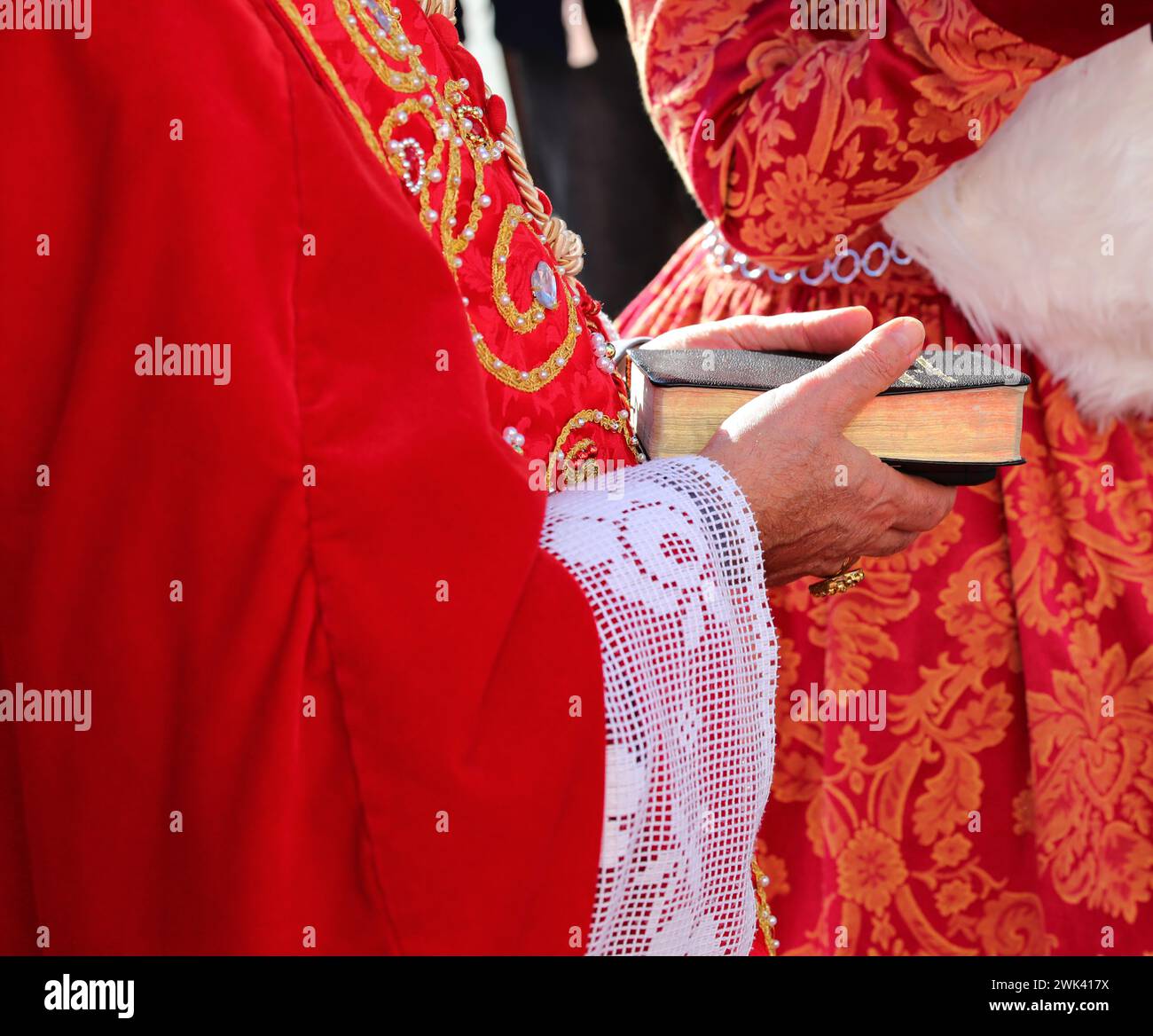 elderly bishop with red cassock and the ancient bible with the sacred ...