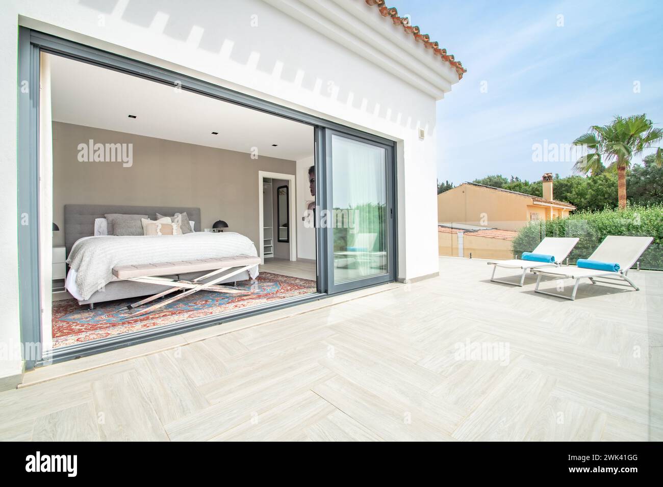 a luxury master bedroom with open balcony doors leading to sunbathing ...