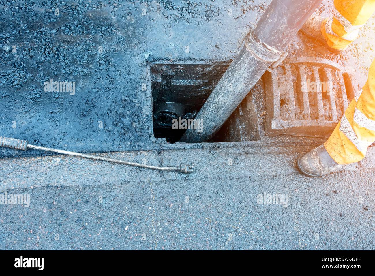 Builder cleaning blocked road gully with shovel and vacuum excavator ...