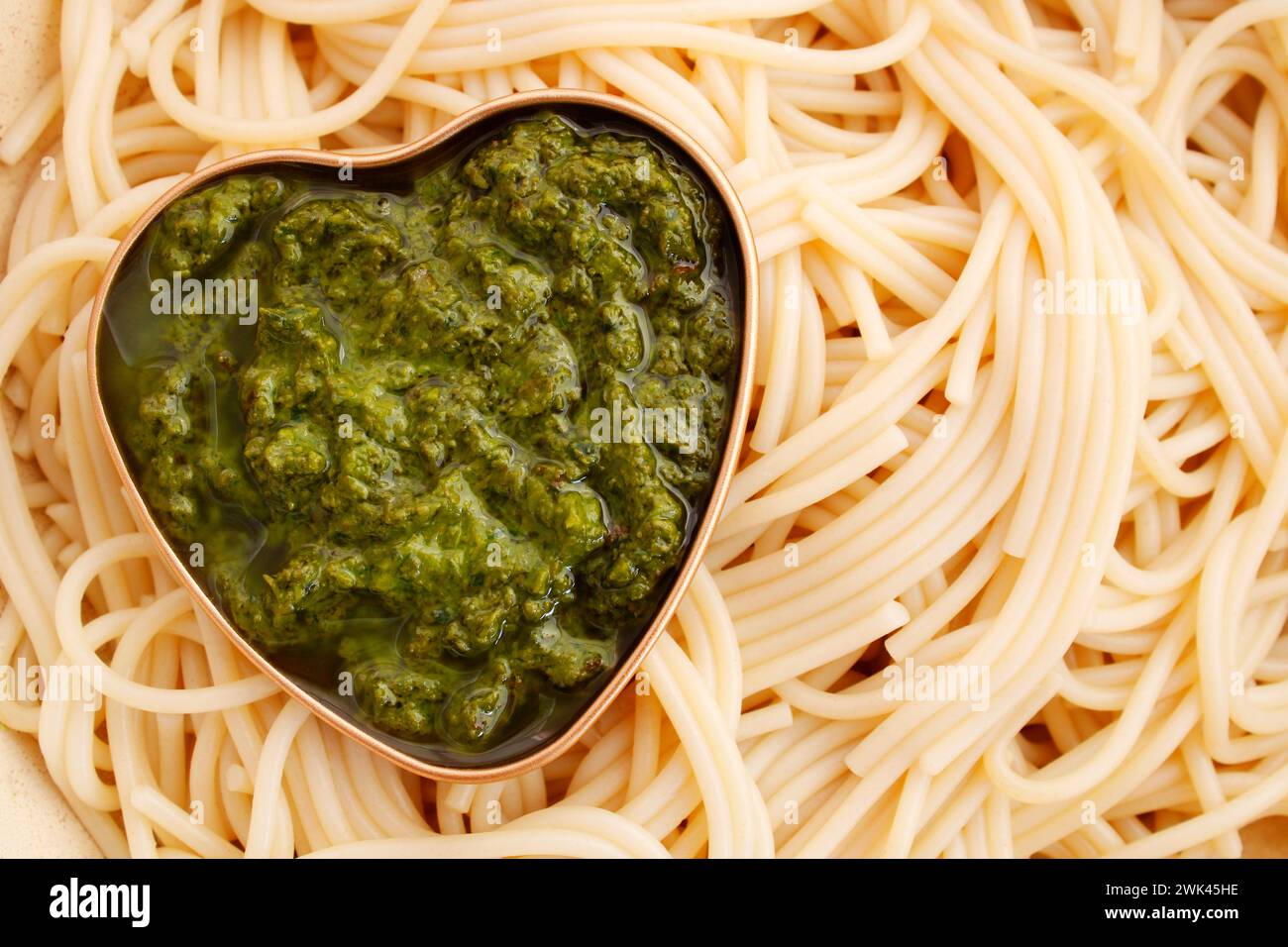 Basil pesto in a heart-shaped container on cooked spaghetti Stock Photo ...