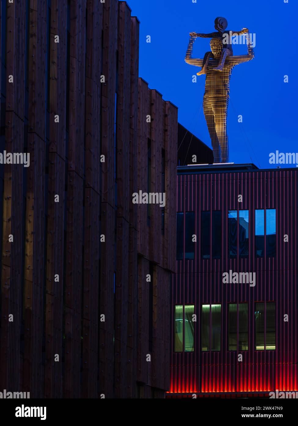 A striking illuminated sculpture of a human figure stands atop a modern ...