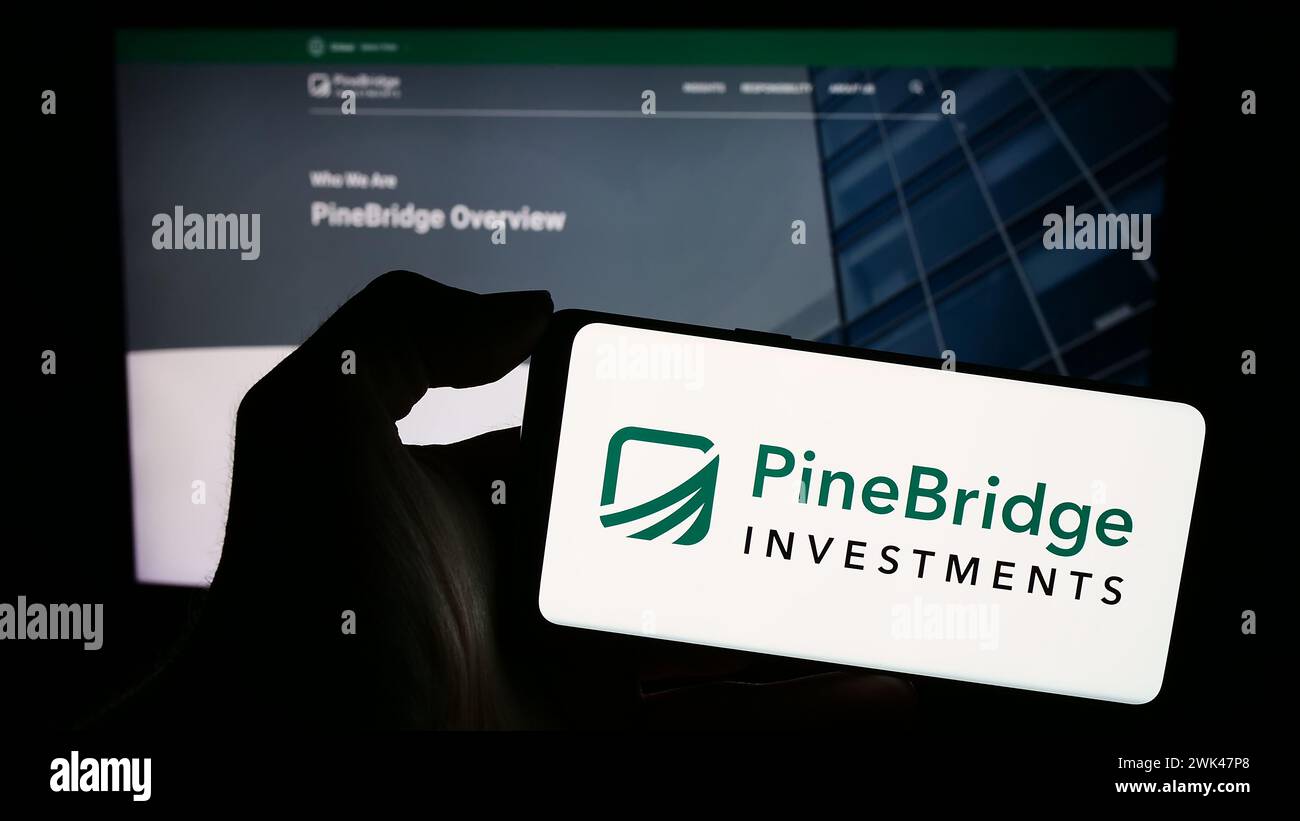 Person holding mobile phone with logo of American investment company ...