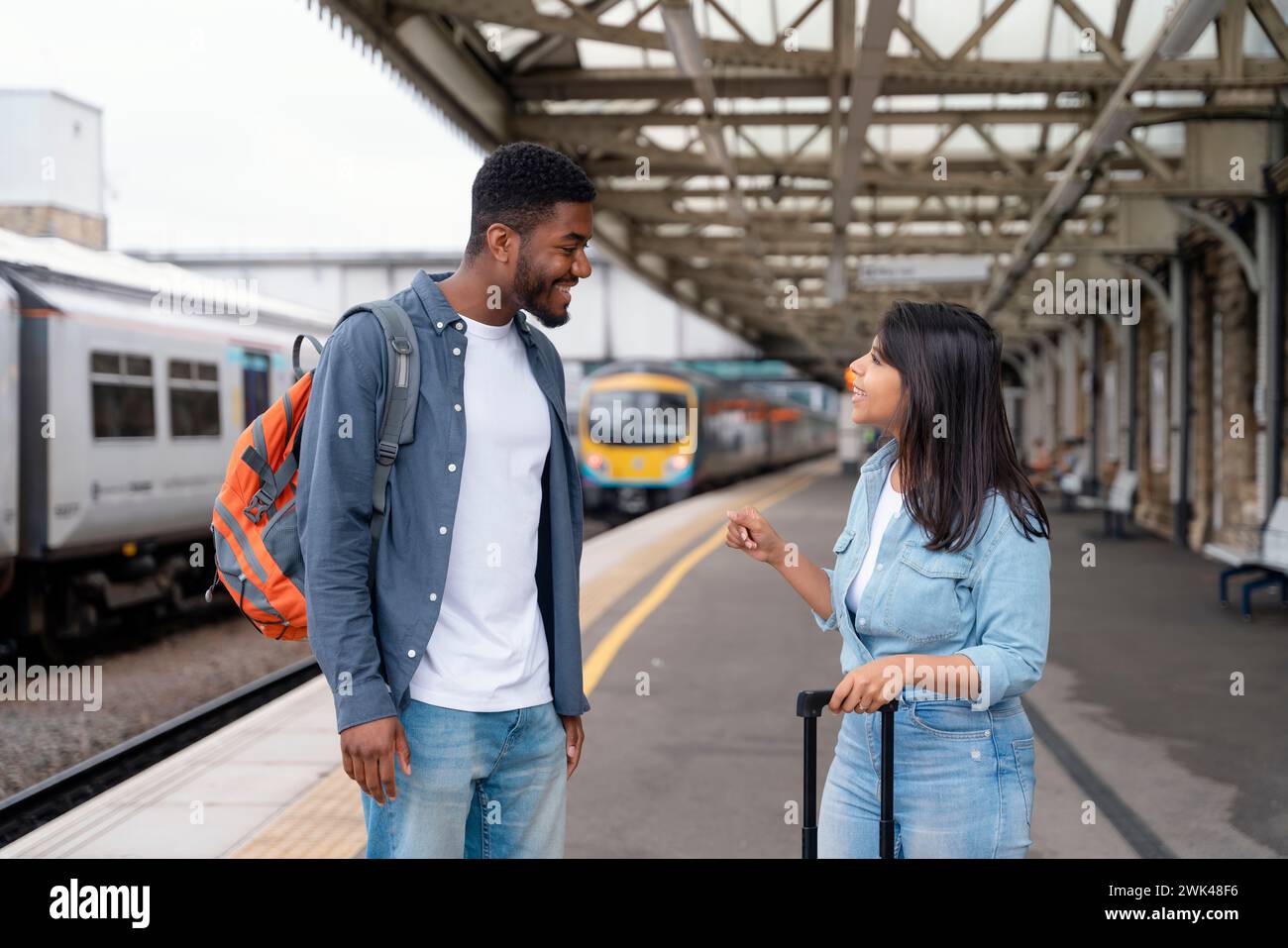 Cheerful couple at railway station waiting for the train on platform ...