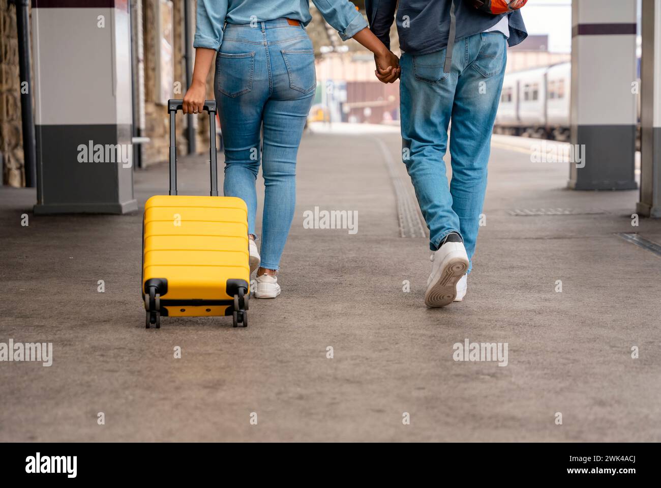 Happy loving couple with luggage and backpack walking along railway ...