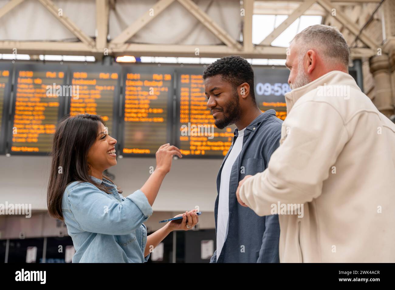 Group of multiracial friends checking time on departure board at a ...