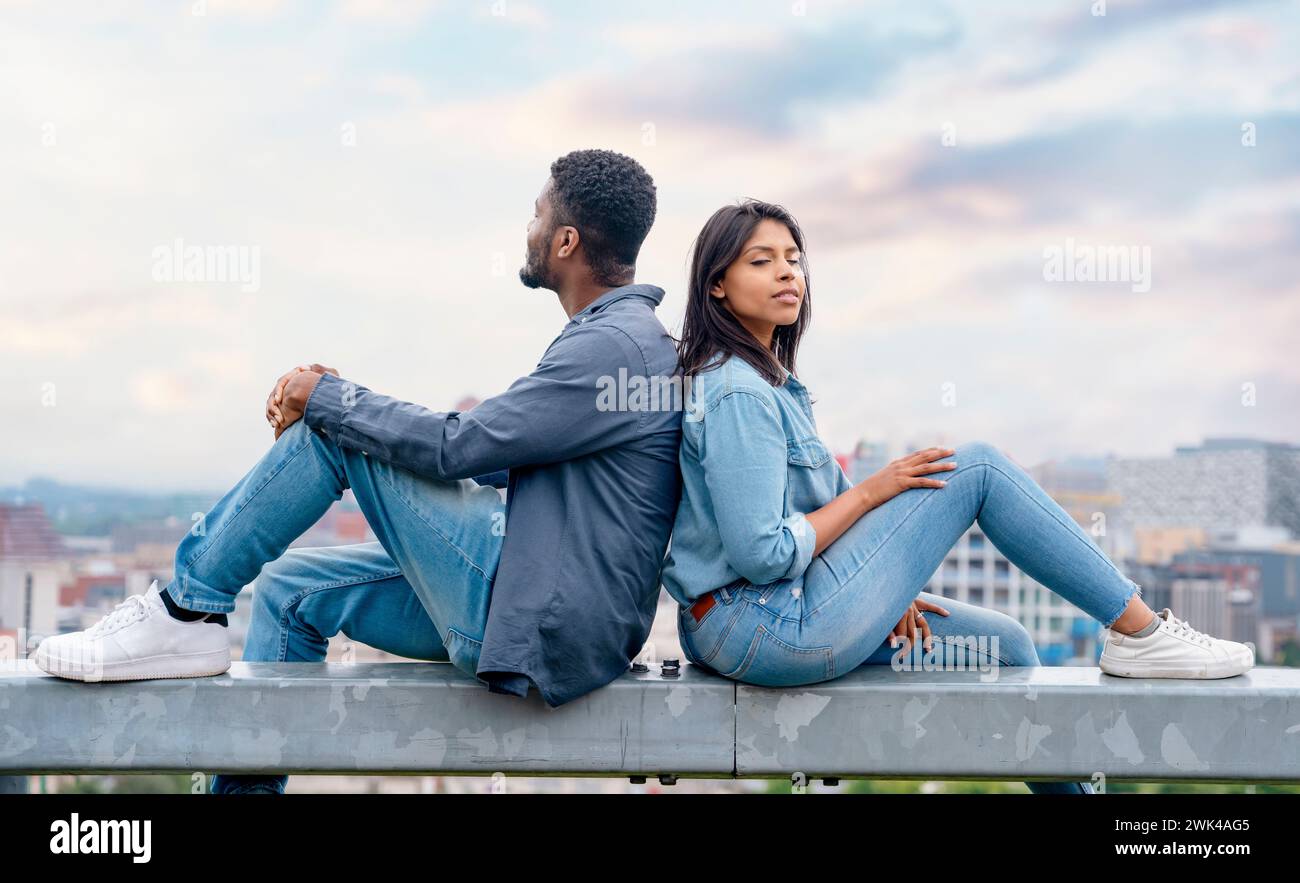 A handsome man and a beautiful woman sitting back to back on the ...