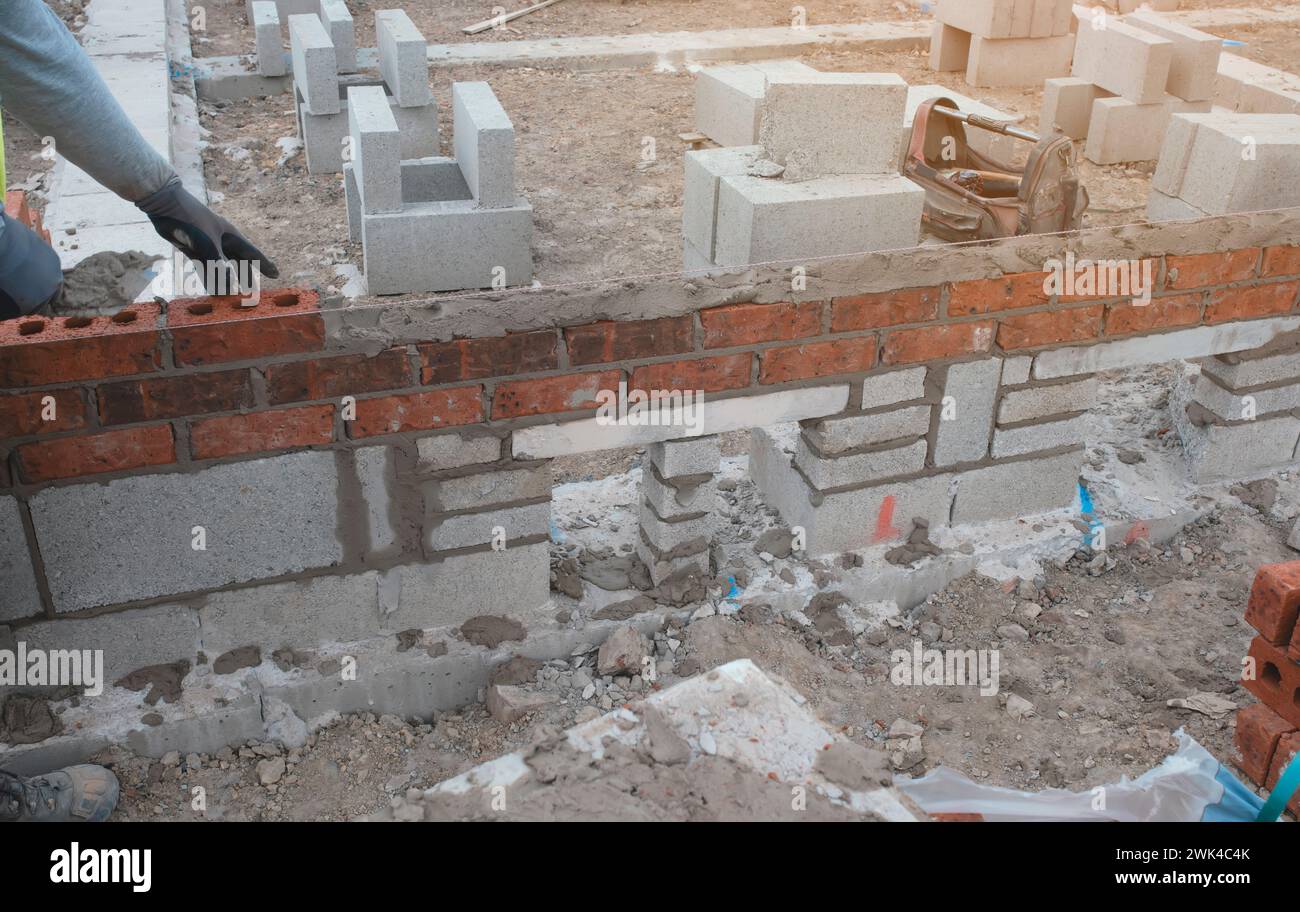 Bricklayer laying brick on cement mix on construction site close-up ...