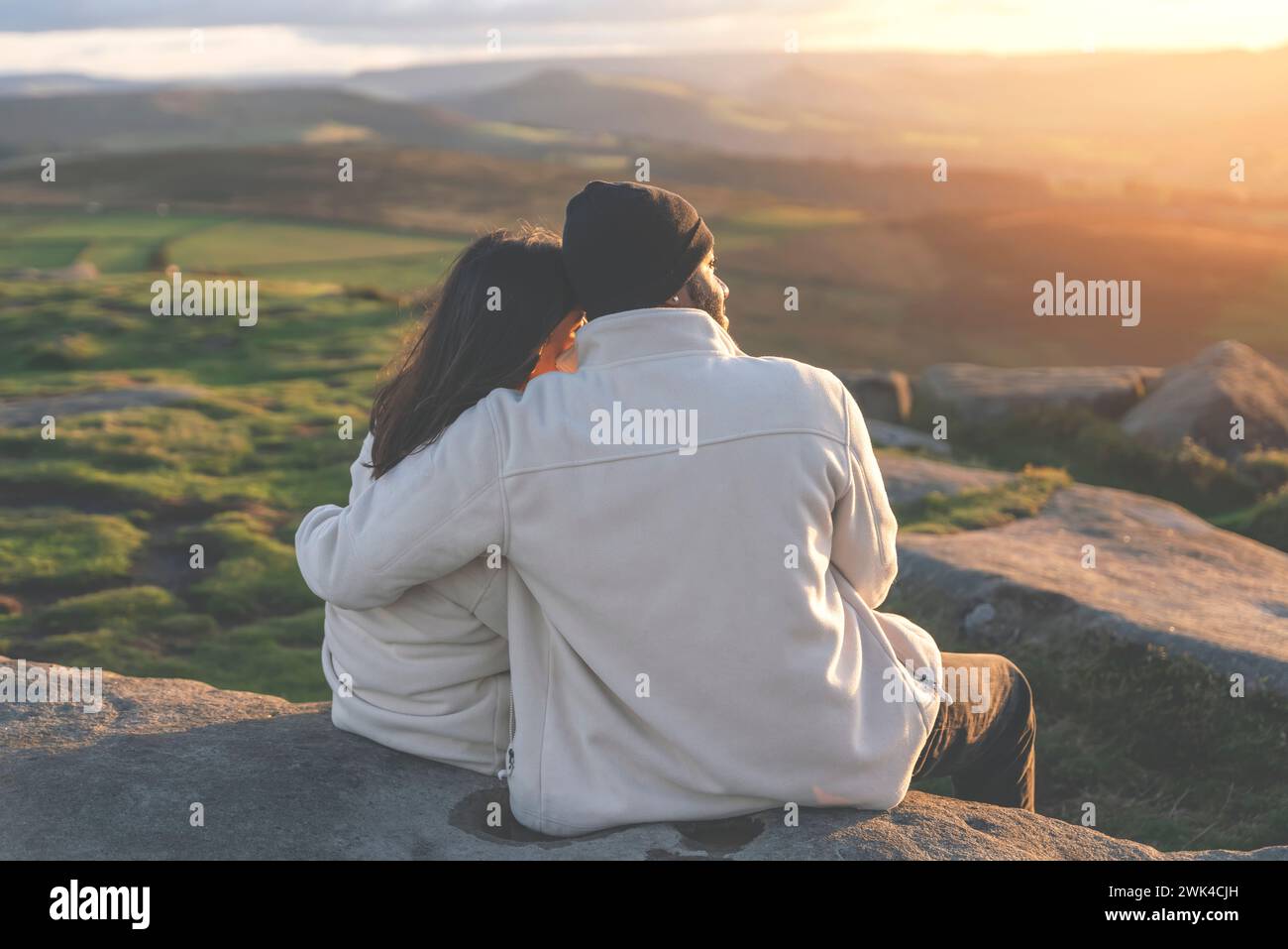 Back view of the happy couple in love sitting on top of a mountain ...