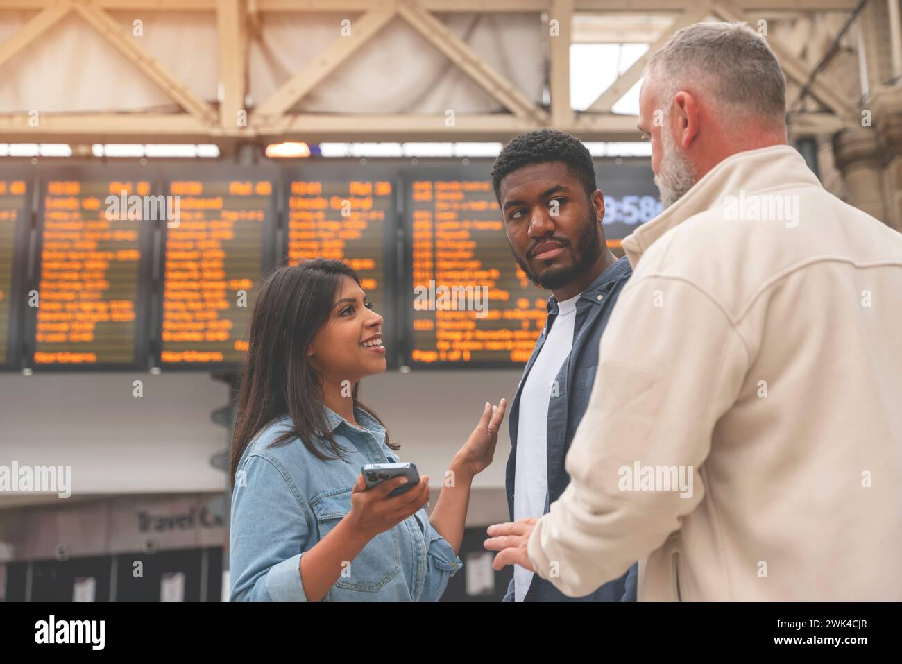 Group of multiracial friends checking time on departure board at a ...