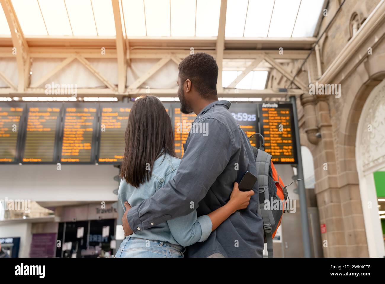 Happy man and woman in love waiting for a train and cuddle at a railway ...