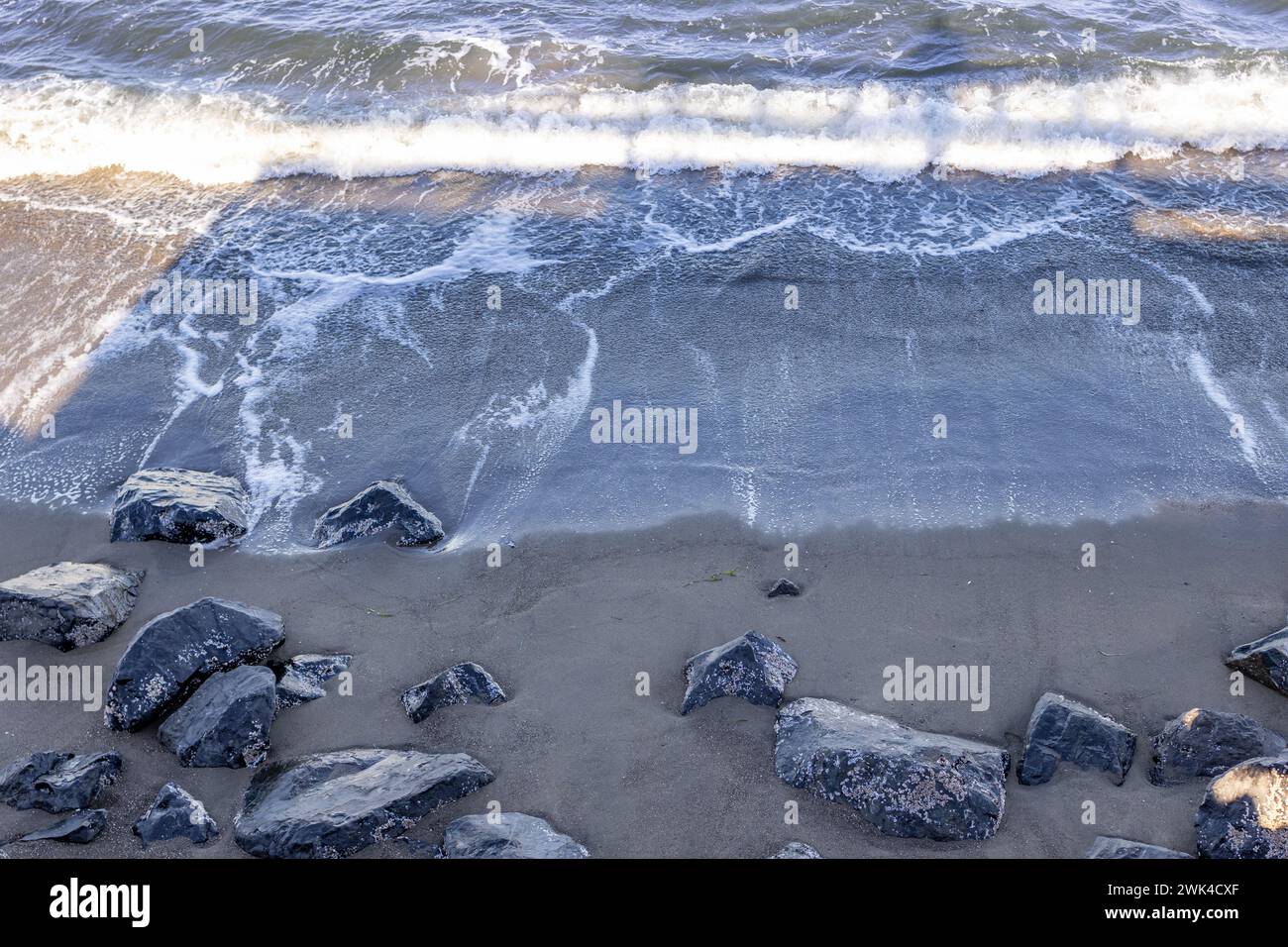 Waves wash over the rocks and sand in the afternoon at Westport WA ...