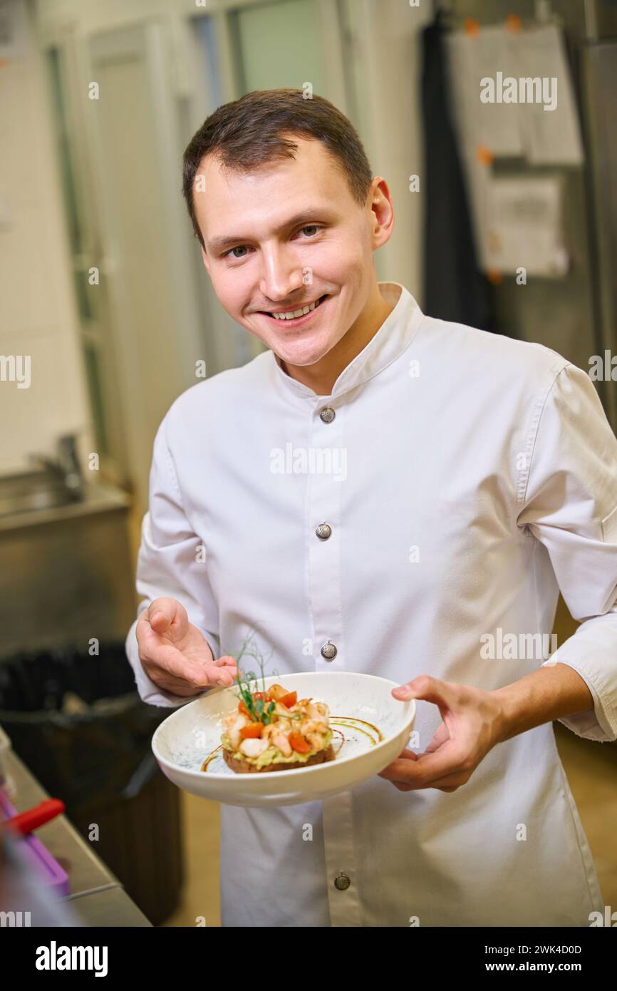 Restaurant kitchen employee presents toast with avocado and shrimp ...